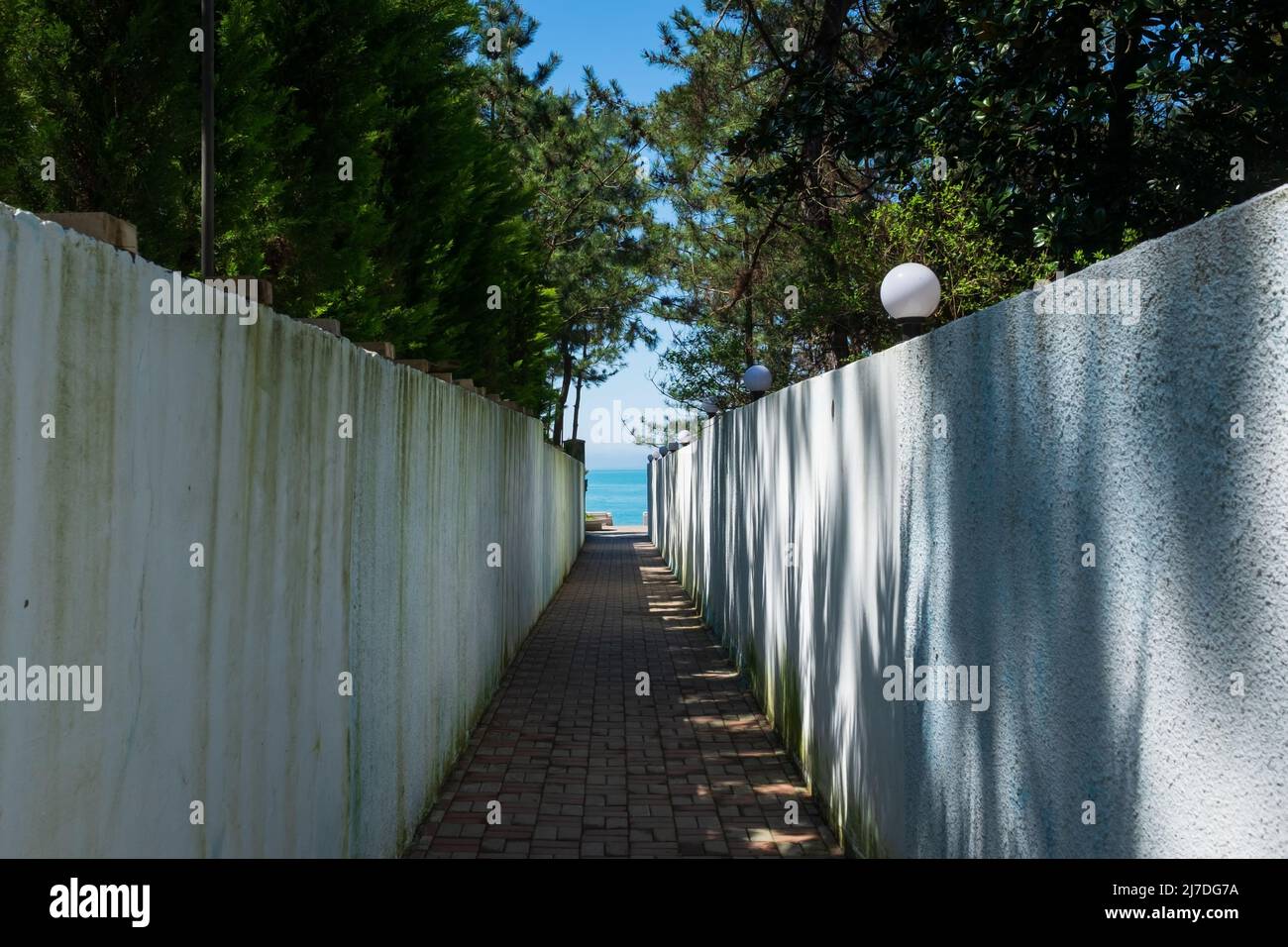 Narrow street leading to the sea. A path between two white walls. Road ...