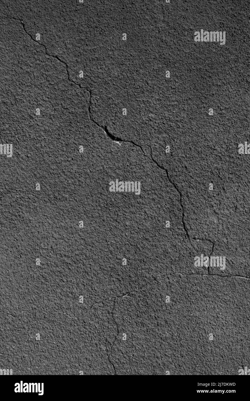 Gray wall with a crack. Texture of rough plaster with uneven granular ...