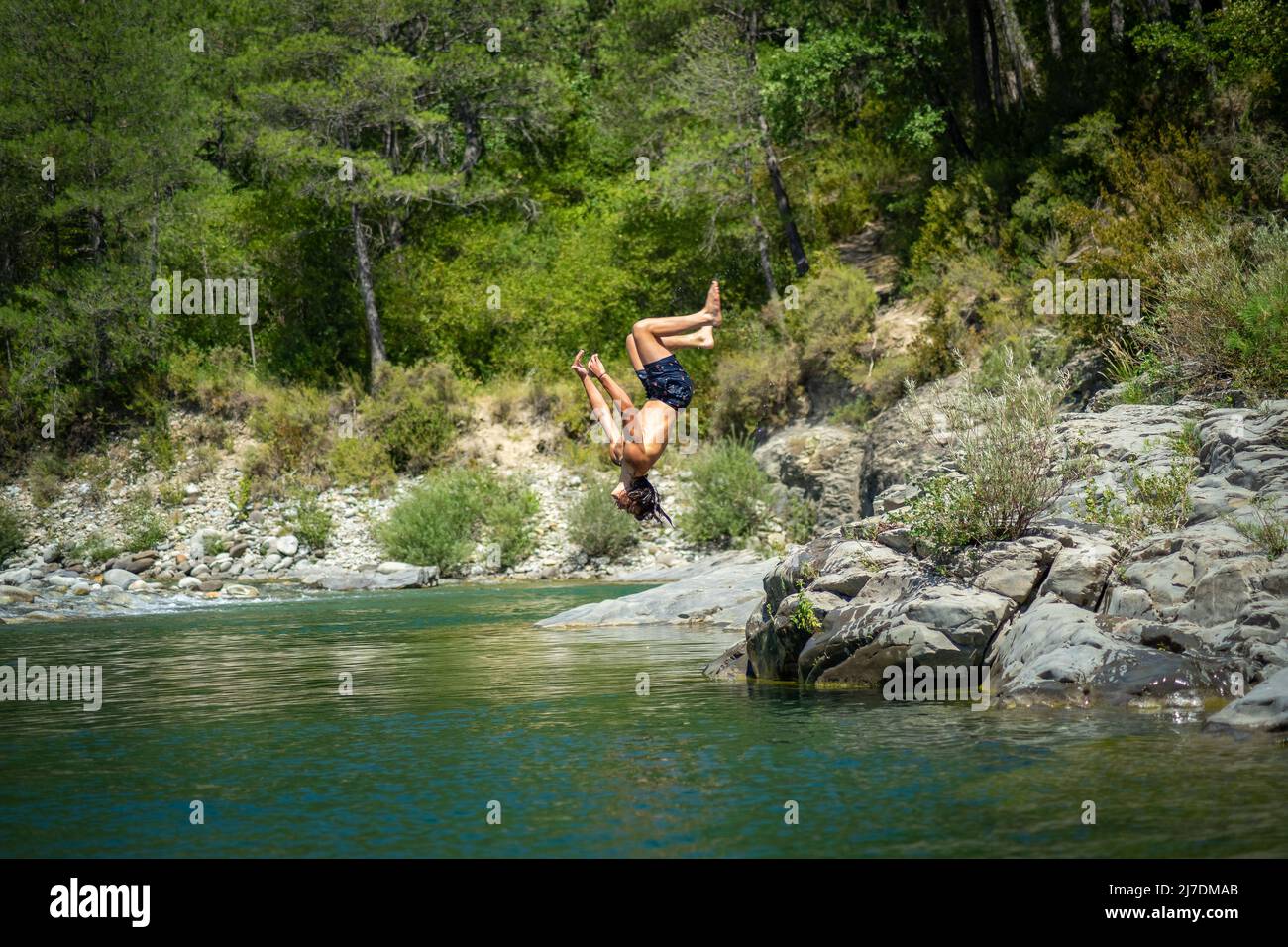 Teenager doing a backflip in Cinca river in aragon forest. Spanish ...