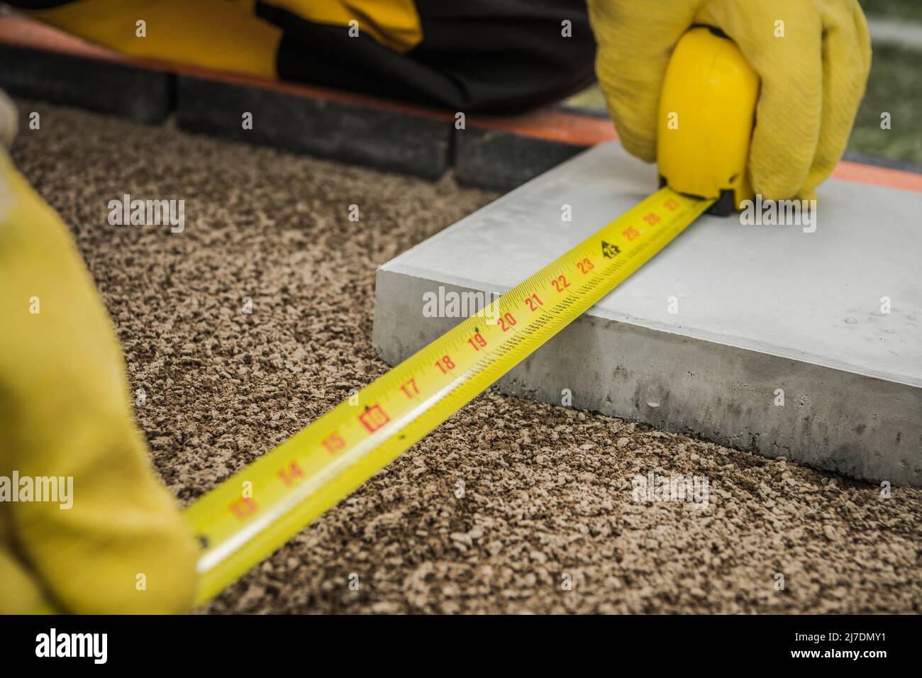 Worker Building Backyard garden Concrete Blocks Path. Compacting Soil ...