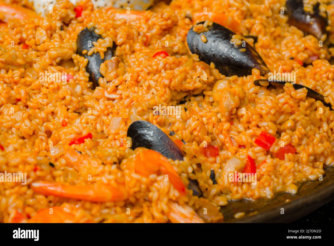 Orange paella with shrimp, mussel, rice, spice, saffron in huge paella ...