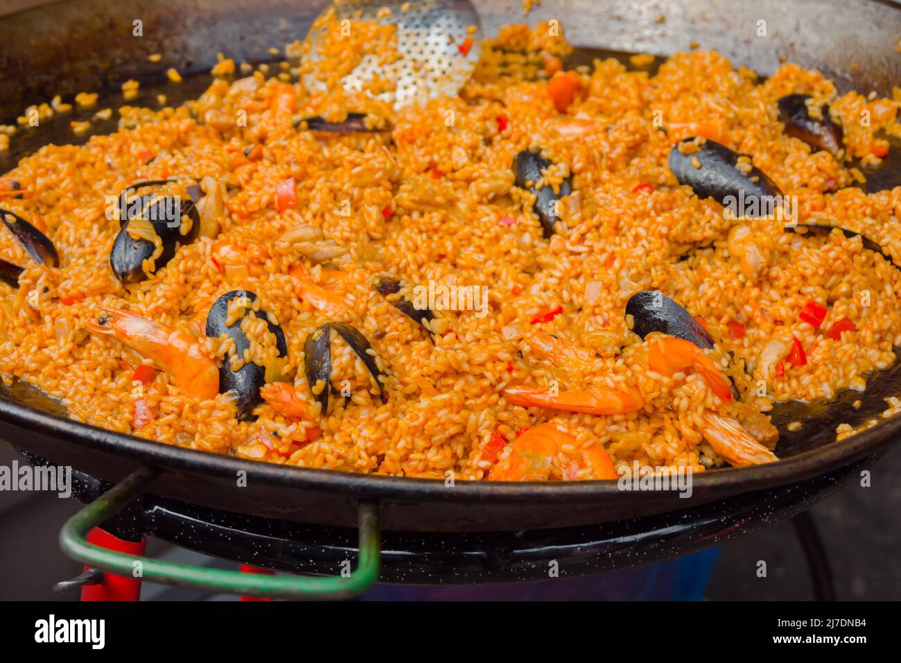 Orange paella with shrimp, mussel, rice, spice, saffron in huge paella ...