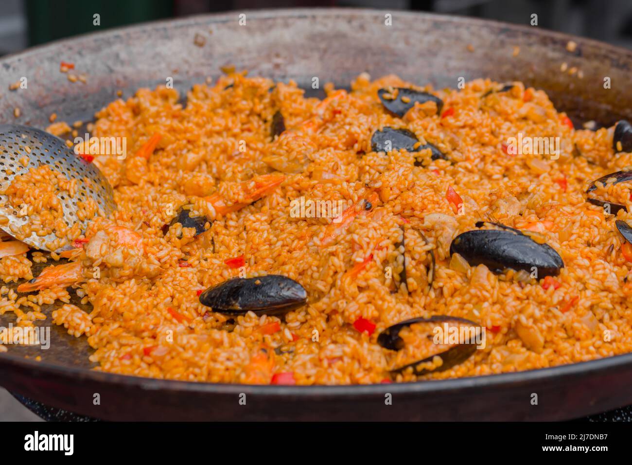Orange paella with shrimp, mussel, rice, spice, saffron in huge paella ...