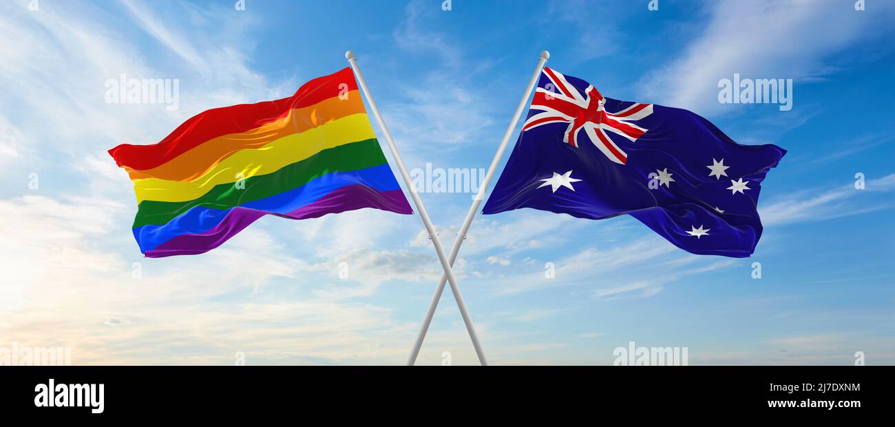 two crossed flags LGBT Pride and Australia waving in wind at cloudy sky ...