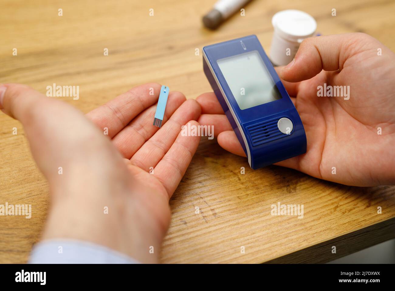 Man hands on the table holding glucometer and stripes for checking ...