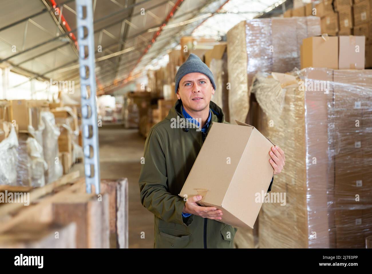 Warehouse worker carrying large box of goods in arehouse Stock Photo ...