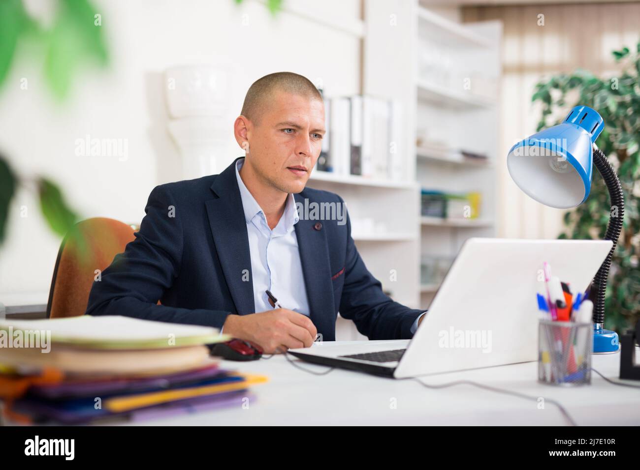 Office employee focused on working with laptop and papers Stock Photo ...