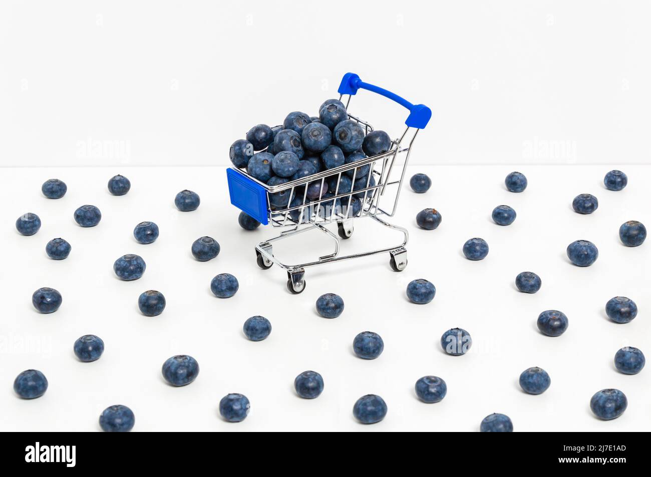 Blueberries in shopping cart and scattered berries isolated on white ...
