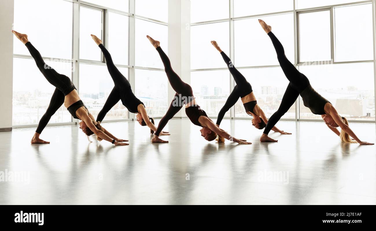 Group of girls in black leggings doing one-legged down dog against ...