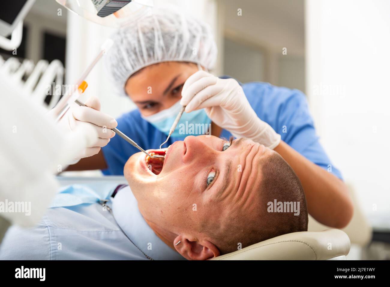 Dentist professional filling teeth for man patient sitting in chair ...