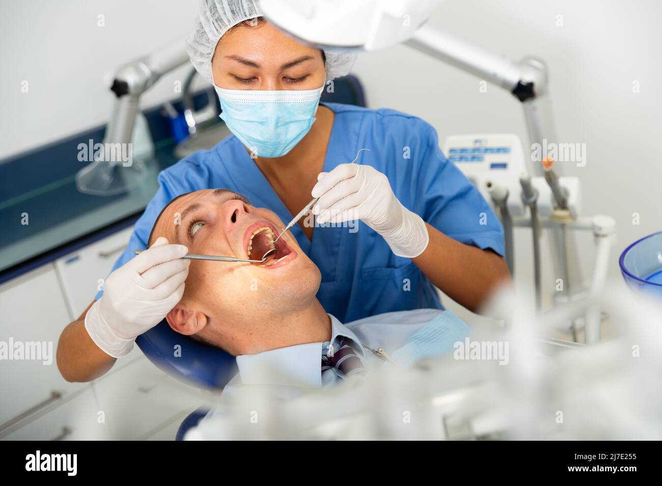 Female dentist examines the oral cavity of female patient. Dental treatment in dental clinic ...