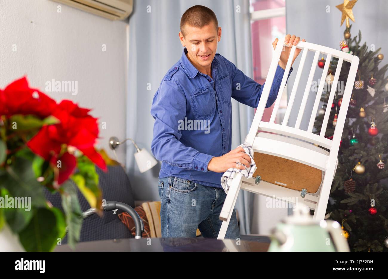 Man wiping dust from chair Stock Photo - Alamy
