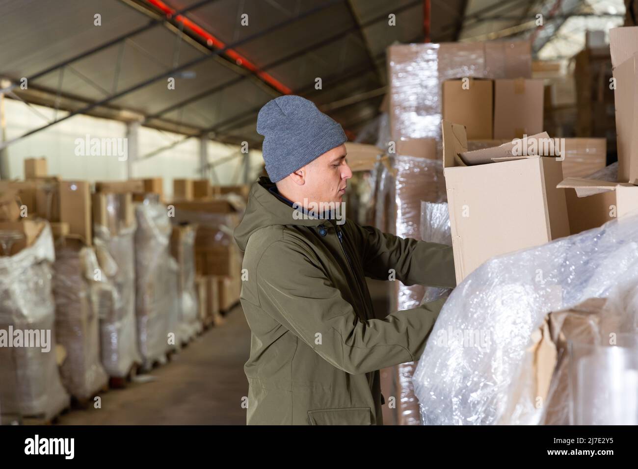 Warehouse worker carrying boxes on racks in in warehouse Stock Photo ...