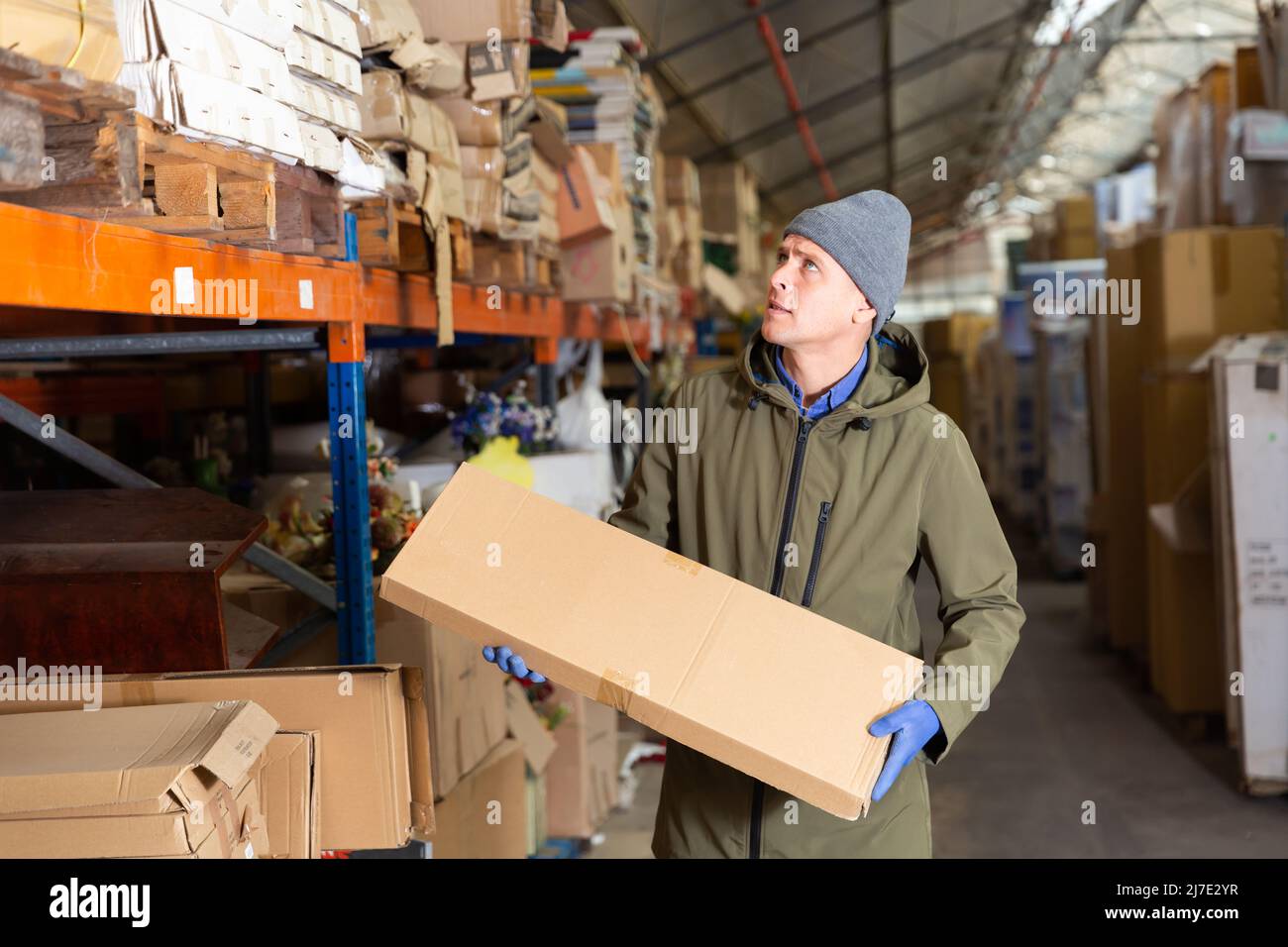 Loader stacks various boxes on racks in store Stock Photo - Alamy