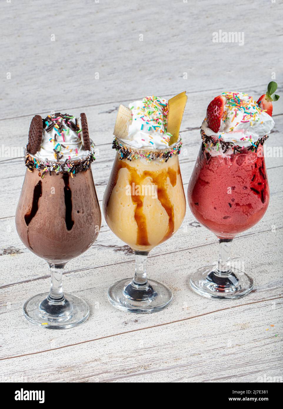 Three glasses of milkshake with assorted flavors. Chocolate, ananas and ...