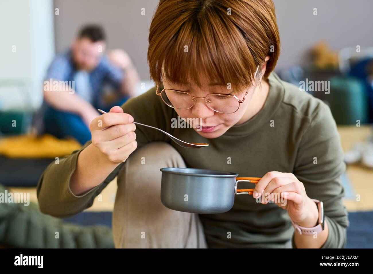 Young Chinese female refugee eating soup or other self prepared food in ...