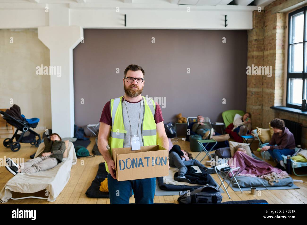 Male volunteer with donation box looking at camera against temporarily ...