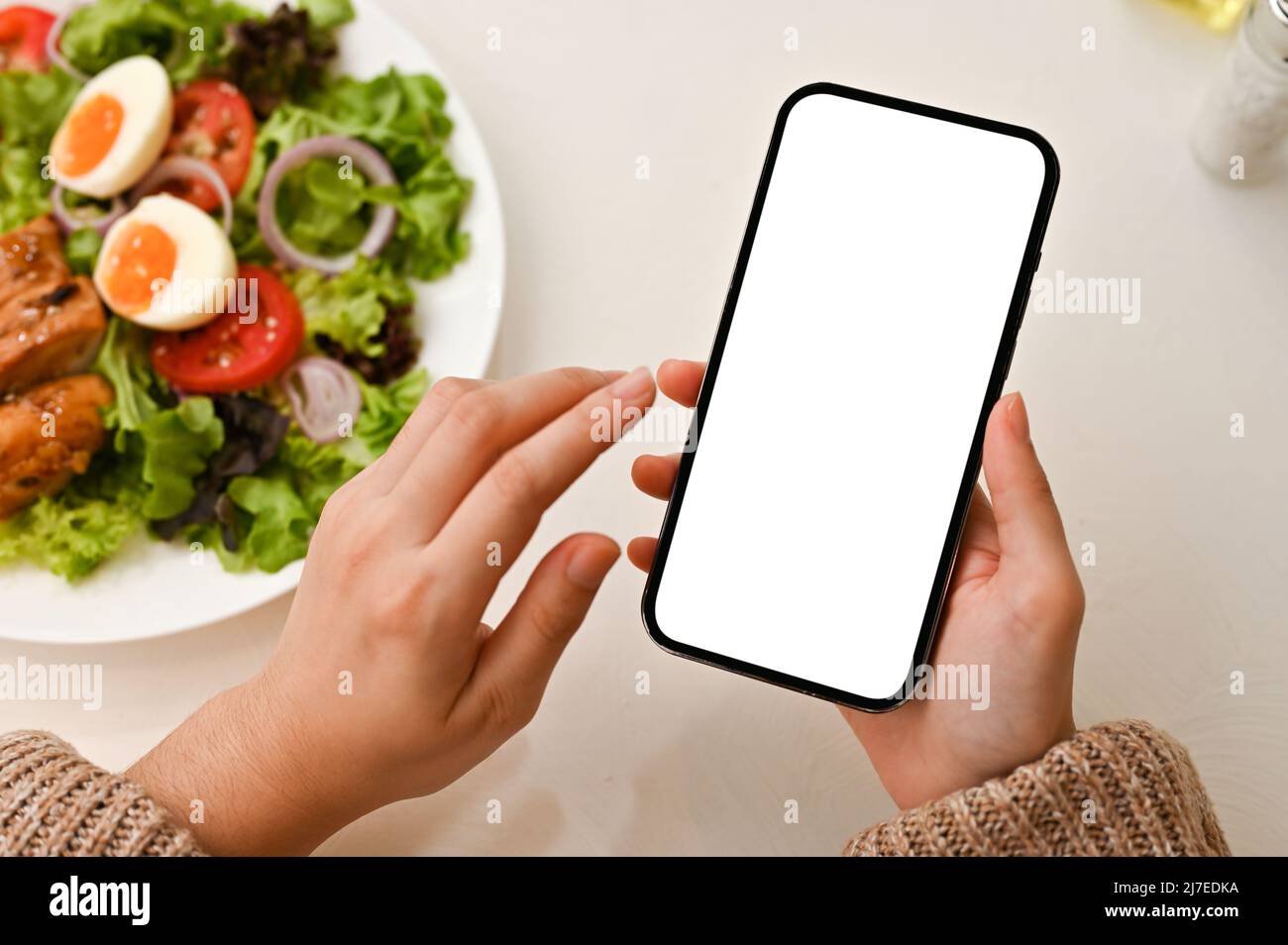 Top view, Female hands using a smartphone, searching healthy menu ...