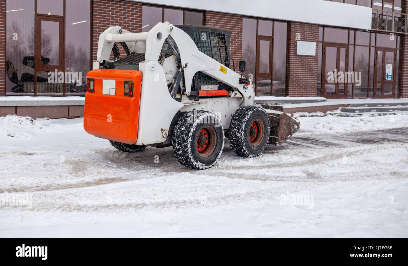Small snow removal vehicle removing snow on city square. Yellow or ...