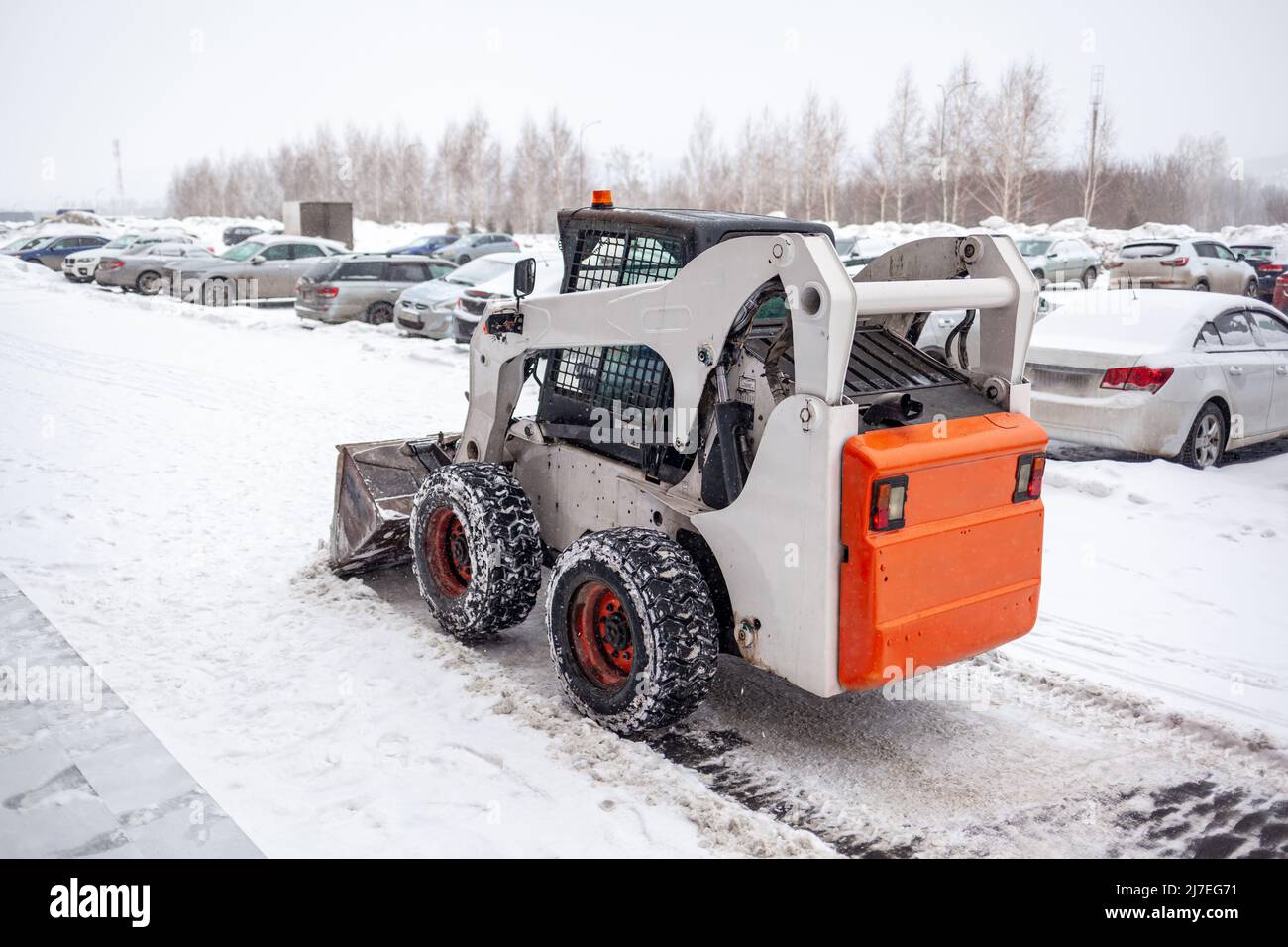 Small snow removal vehicle removing snow on city square. Yellow or ...