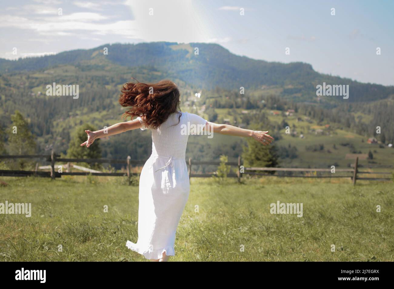 Happy young woman is turning round in the field. Freedom feeling in the ...