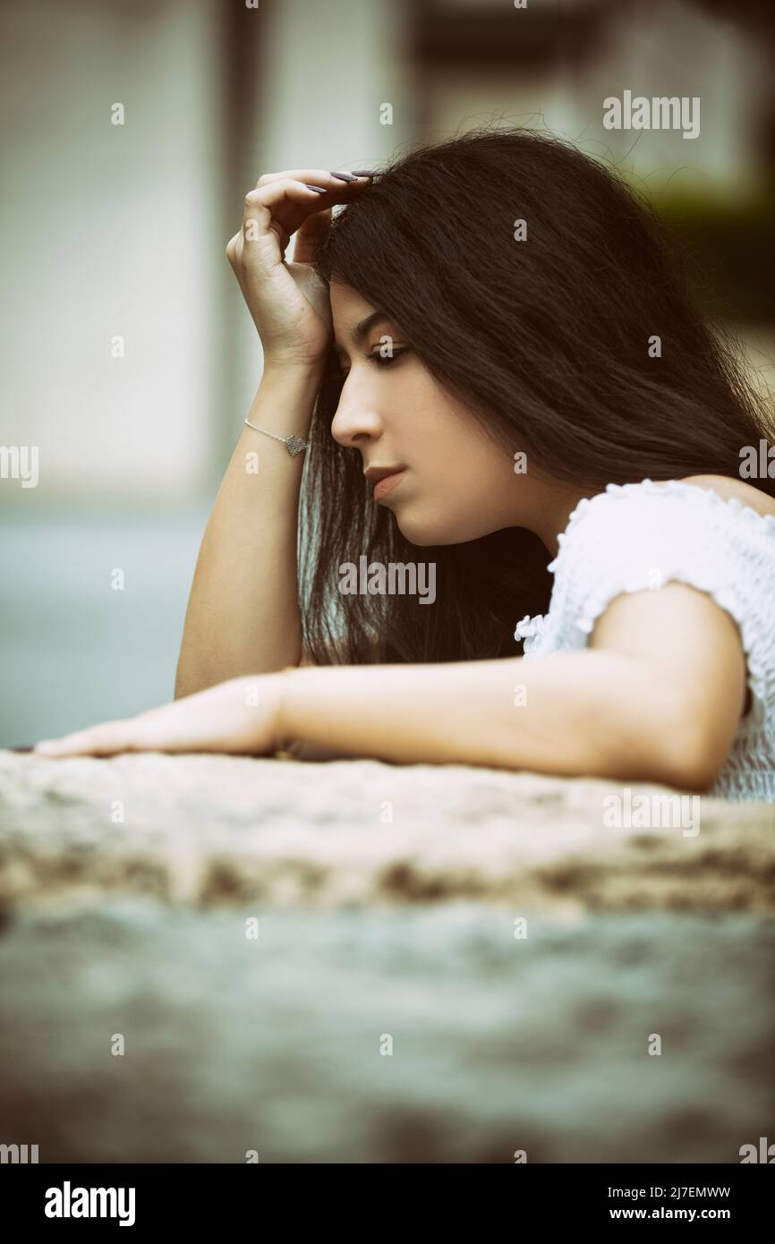 Sad woman sitting outdoors Stock Photo - Alamy