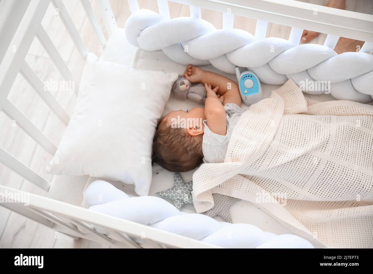 Cute little child with toy and baby monitor sleeping in crib Stock ...