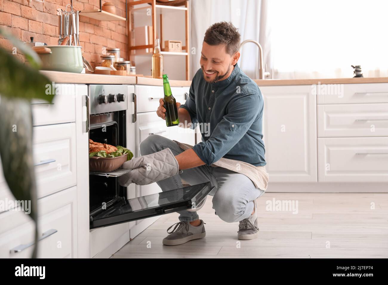 Handsome man drinking beer while cooking in kitchen Stock Photo - Alamy