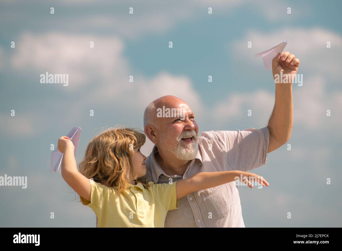 Grandson child and grandfather with paper plane over blue sky and ...