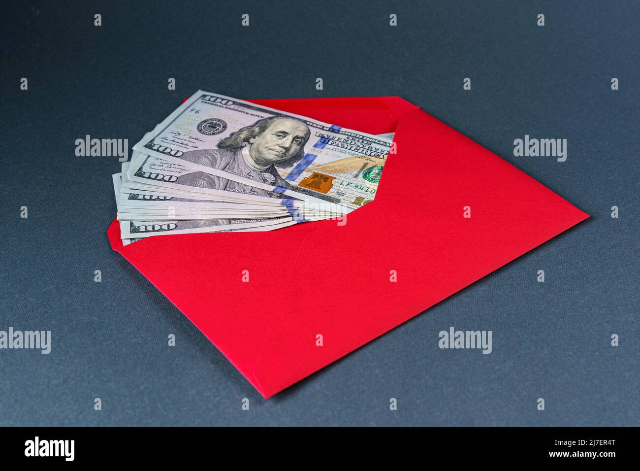 Open red paper envelope with hundred dollar bills on gray background ...
