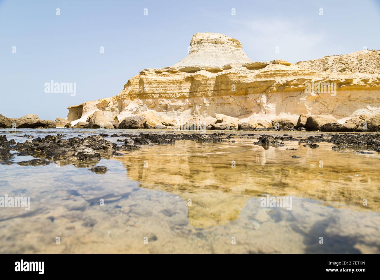 Xwejni rock formation reflecting in the rock pools at low tide on the ...