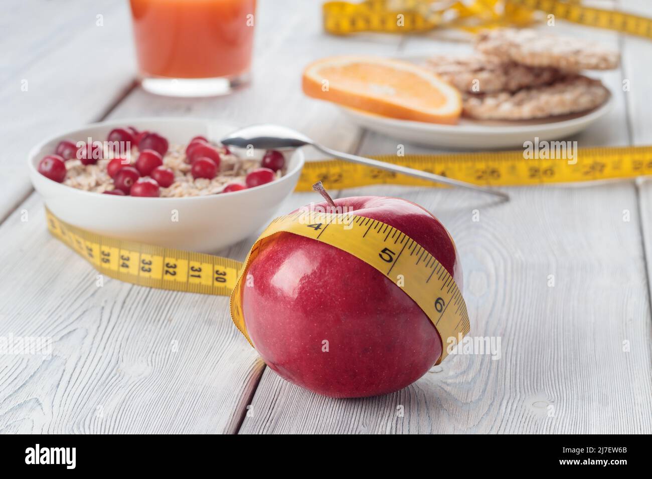 Red apple and cranberry and crispbreads and orange juice with tape ...