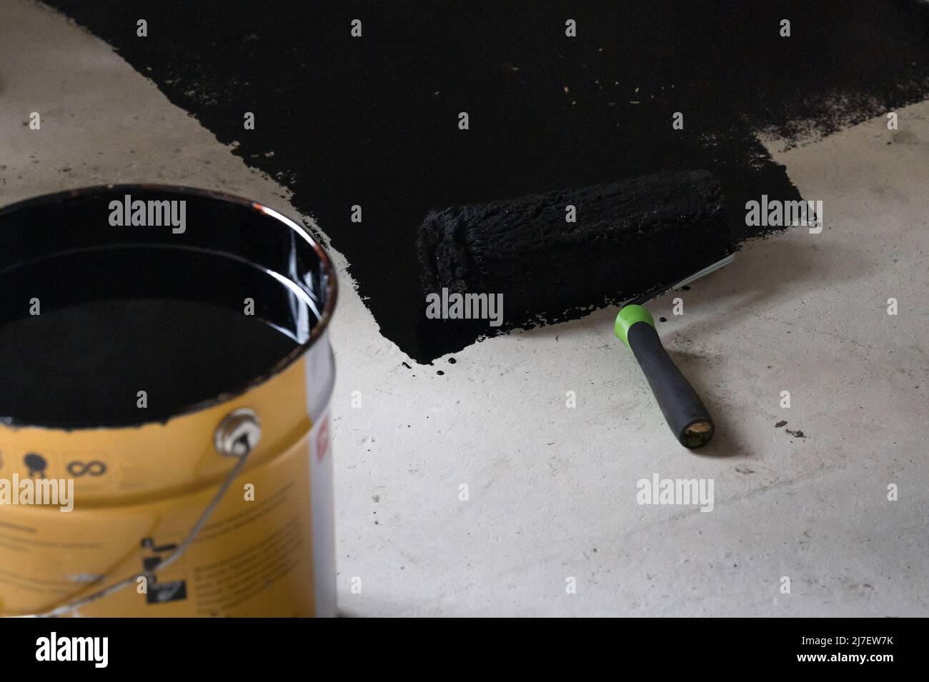 Applying hot resin to the floor for waterproofing, roller and bucket of ...