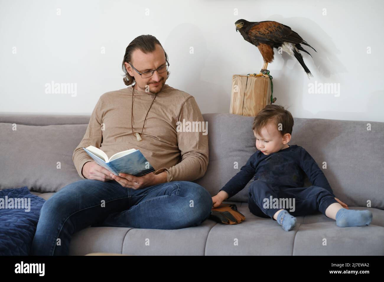 Father with child and wild bird buzzard sitting on the coach, reading ...