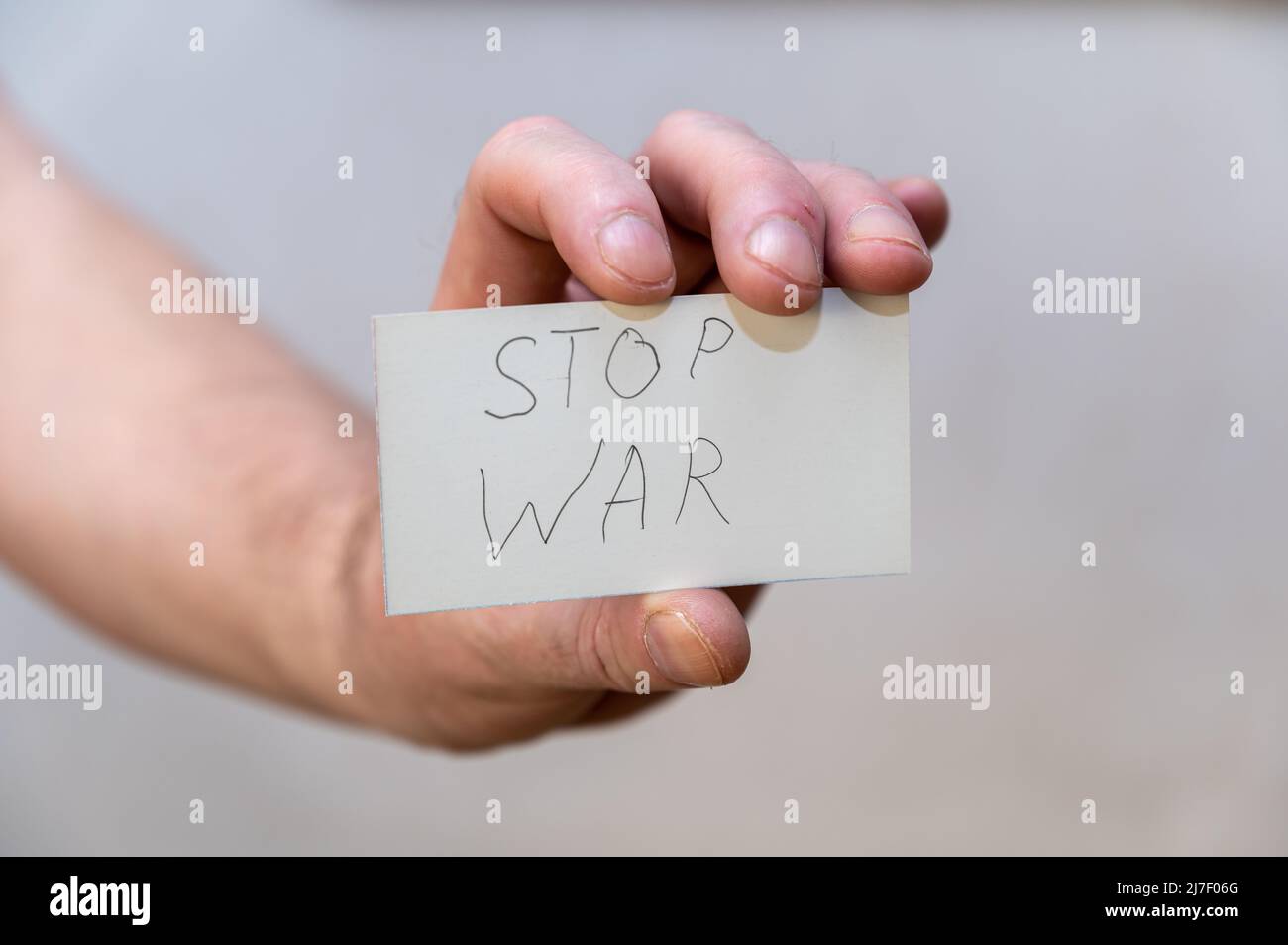 Stop War. Words written in jagged letters. A man's hand holds a white ...