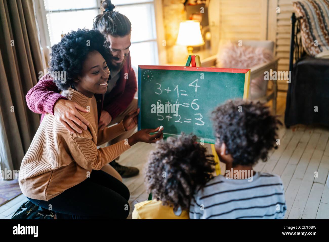 Happy children learning maths with multiethnic parents at home. Family ...