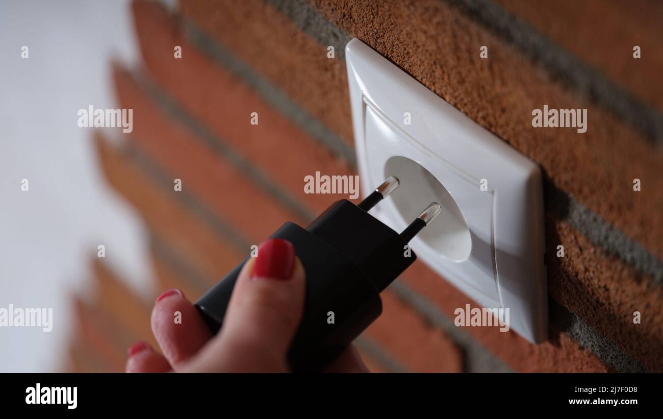 Woman holding hand and inserting plug into socket closeup Stock Photo ...