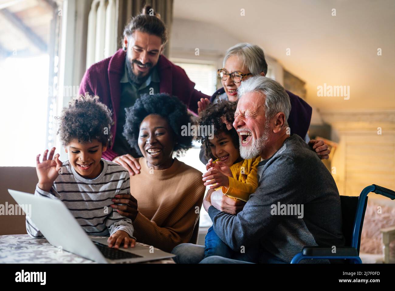 Extended multiethnic family together at home during video call. People ...