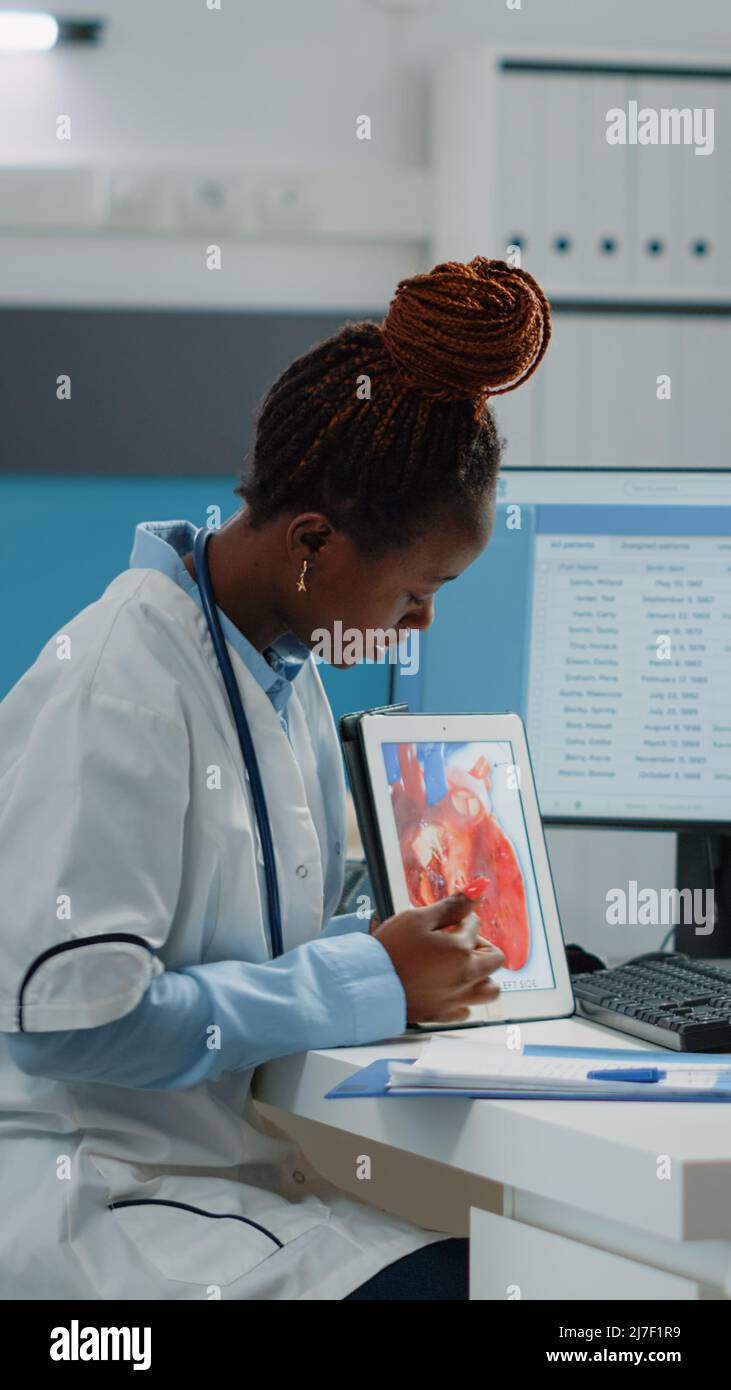 Doctor pointing at tablet with cardiovascular figure, explaining heart ...