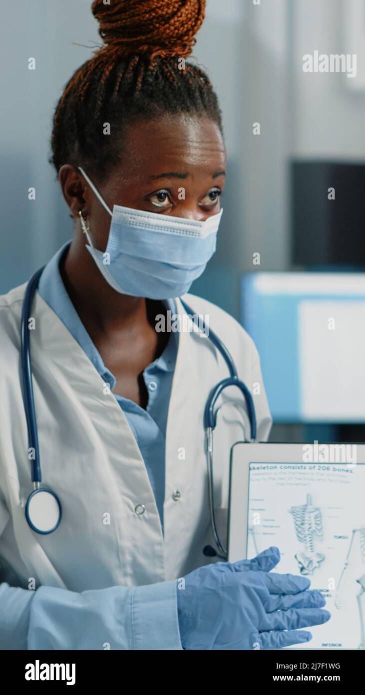 Medic showing tablet with human skeleton to patient for osteopathy ...