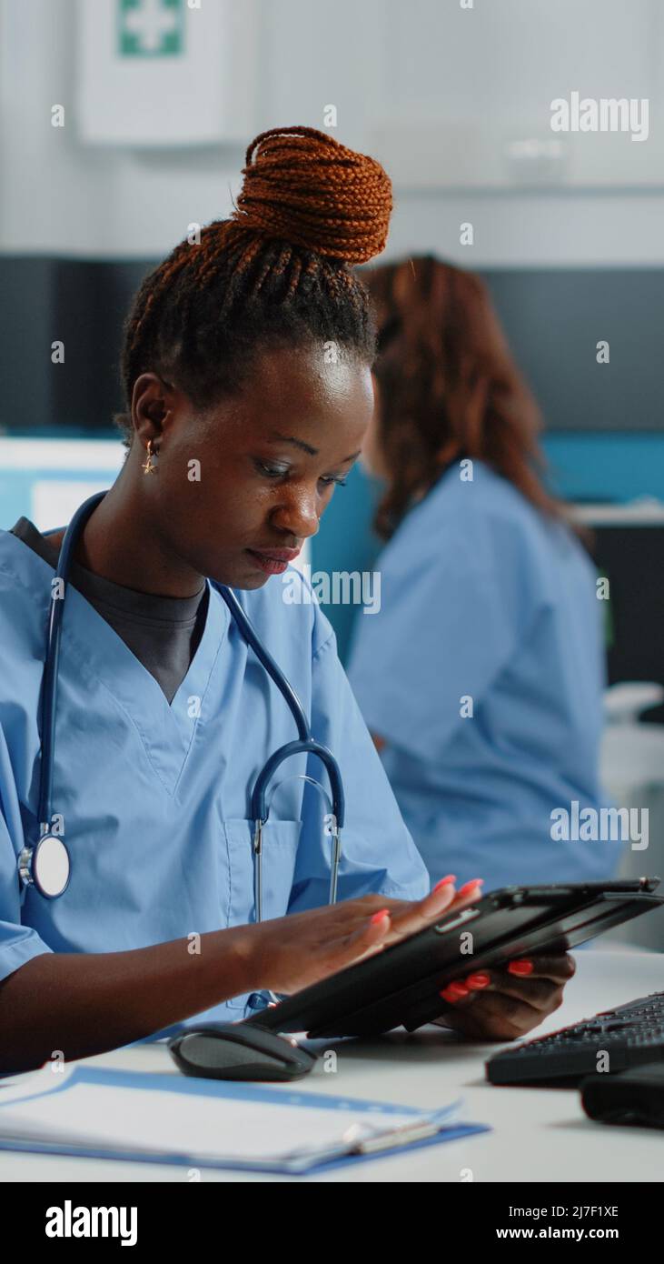 African american nurse holding digital tablet for checkup visit in ...