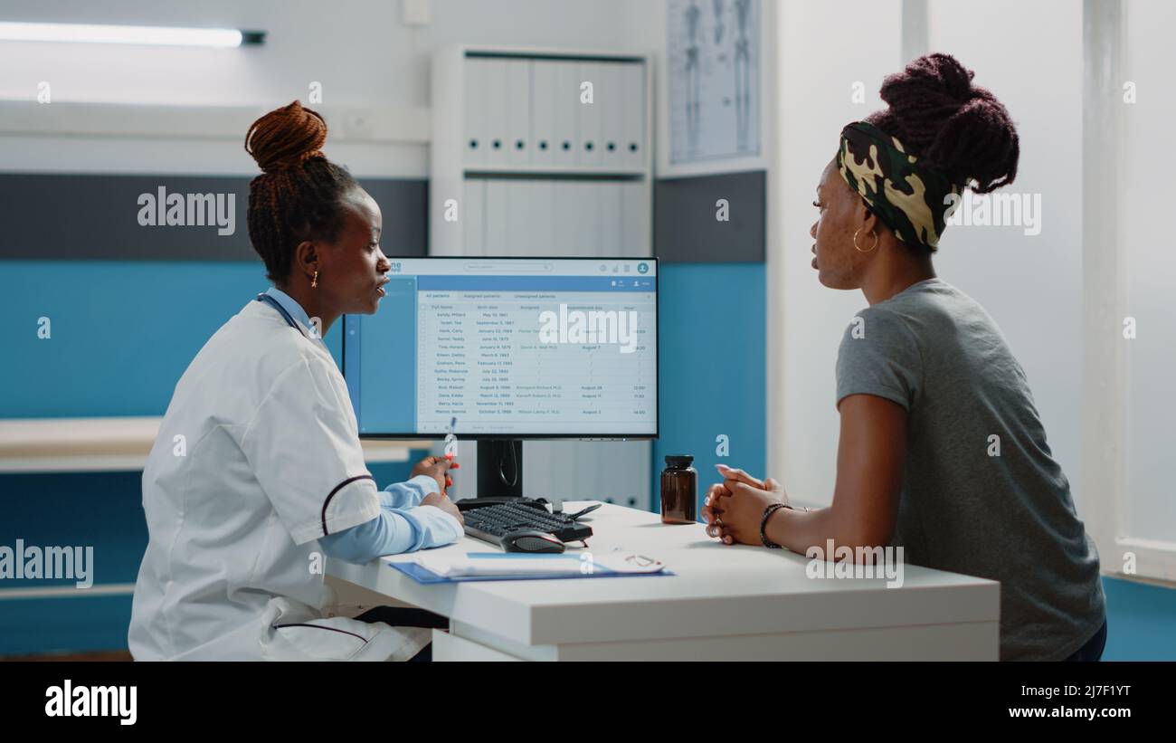African american doctor and woman looking at computer screen for ...