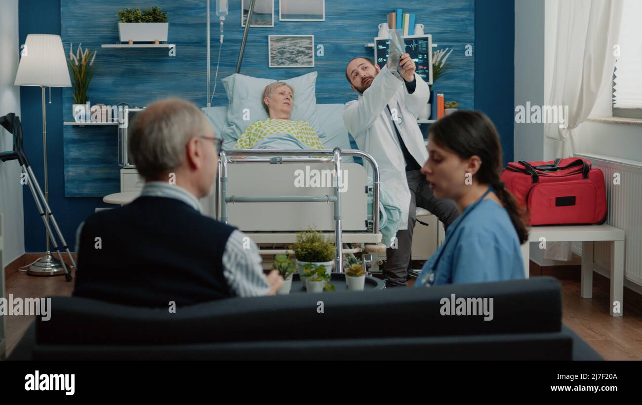 Doctor showing x ray scan to senior woman laying in hospital bed. Medic ...