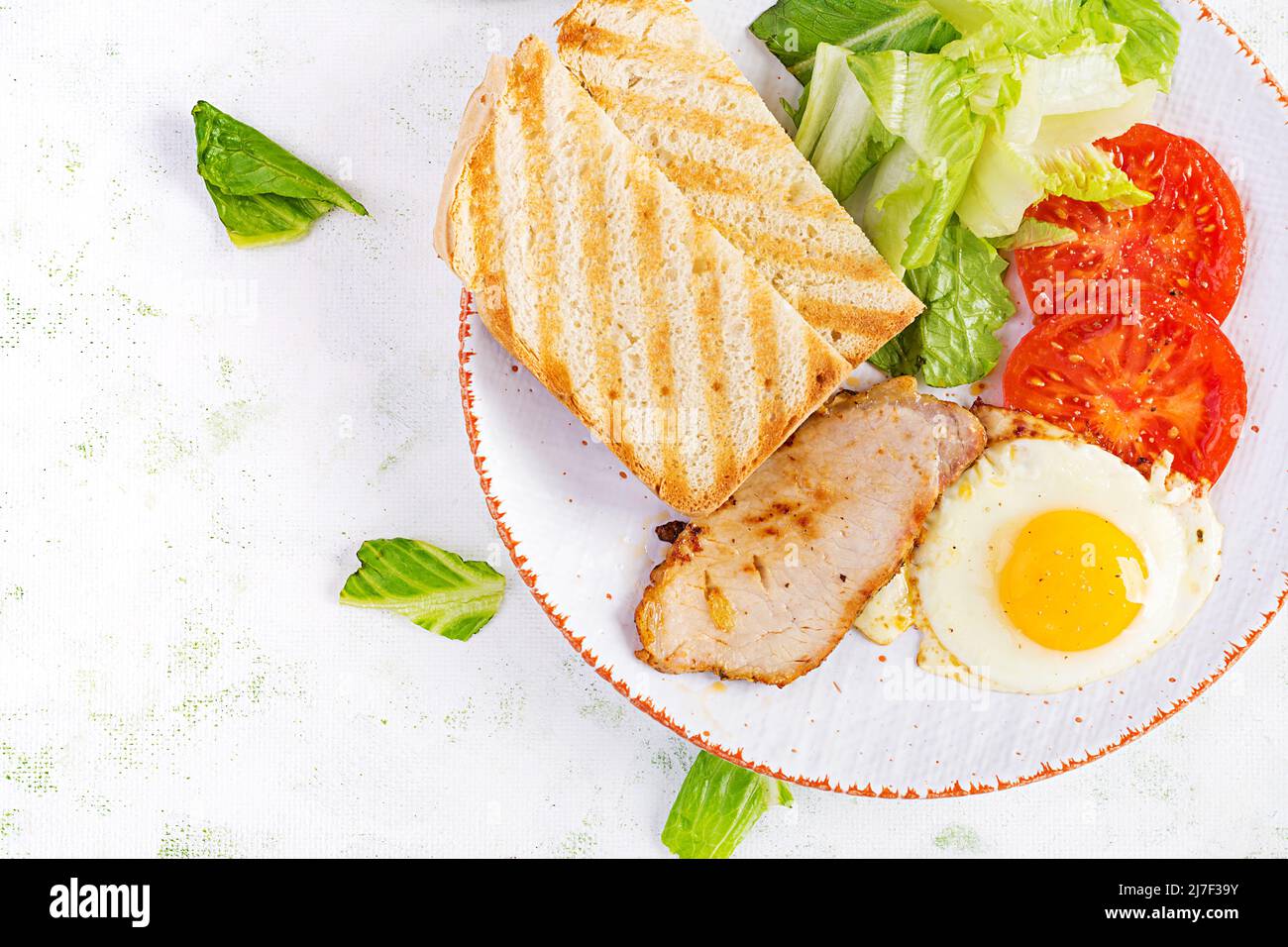 Fried egg with slice pork, tomatoes and toasts. Delicious English ...