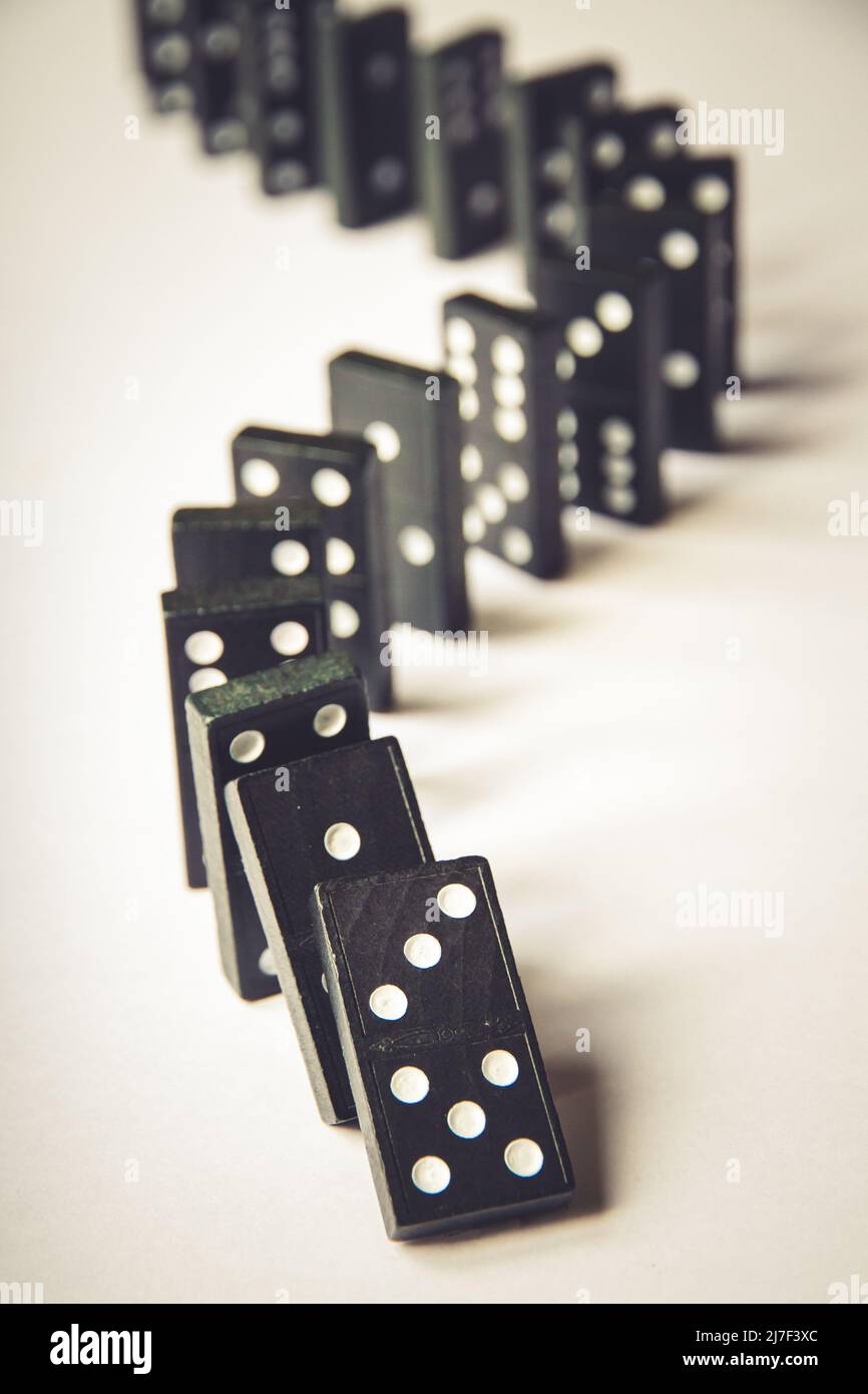 Black dominoes chain on a white table background. Domino effect concept ...