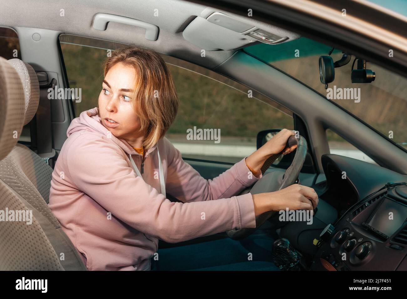 Portrait of frightened young caucasian woman driving a left-handed car ...