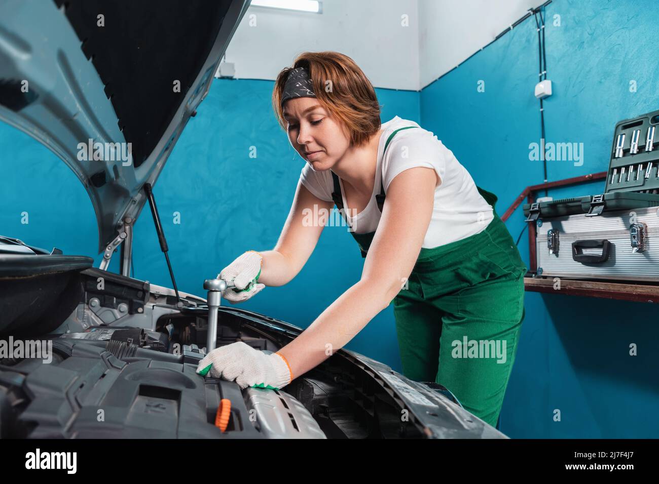 Mechanic woman in green coveralls repair a engine. The concept of woman ...