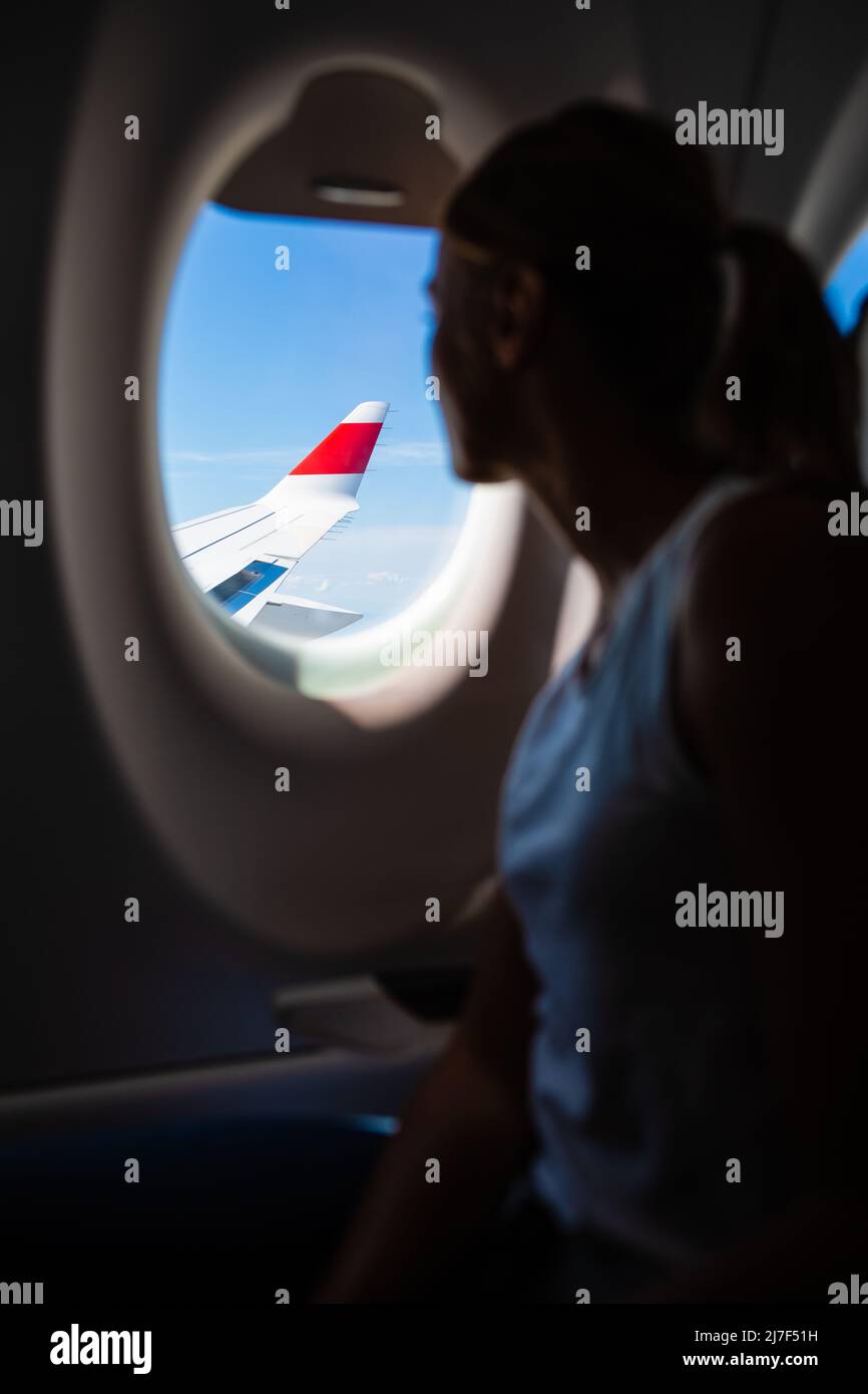 Young woman looking out of the window during a flight on a commercial ...
