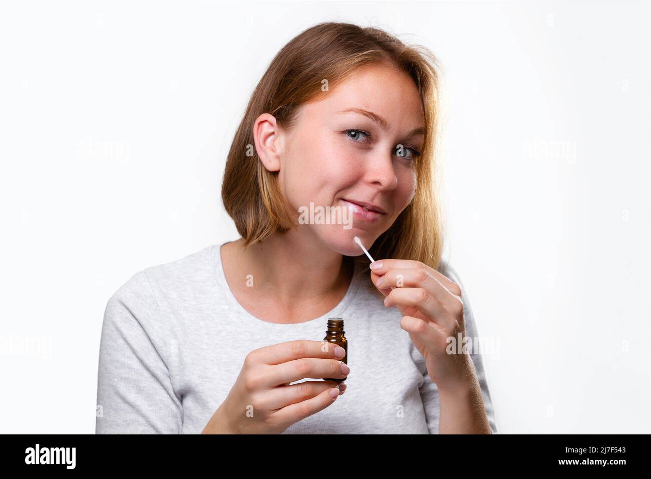 Portrait of a young caucasian woman smearing medicine on a pimple on ...