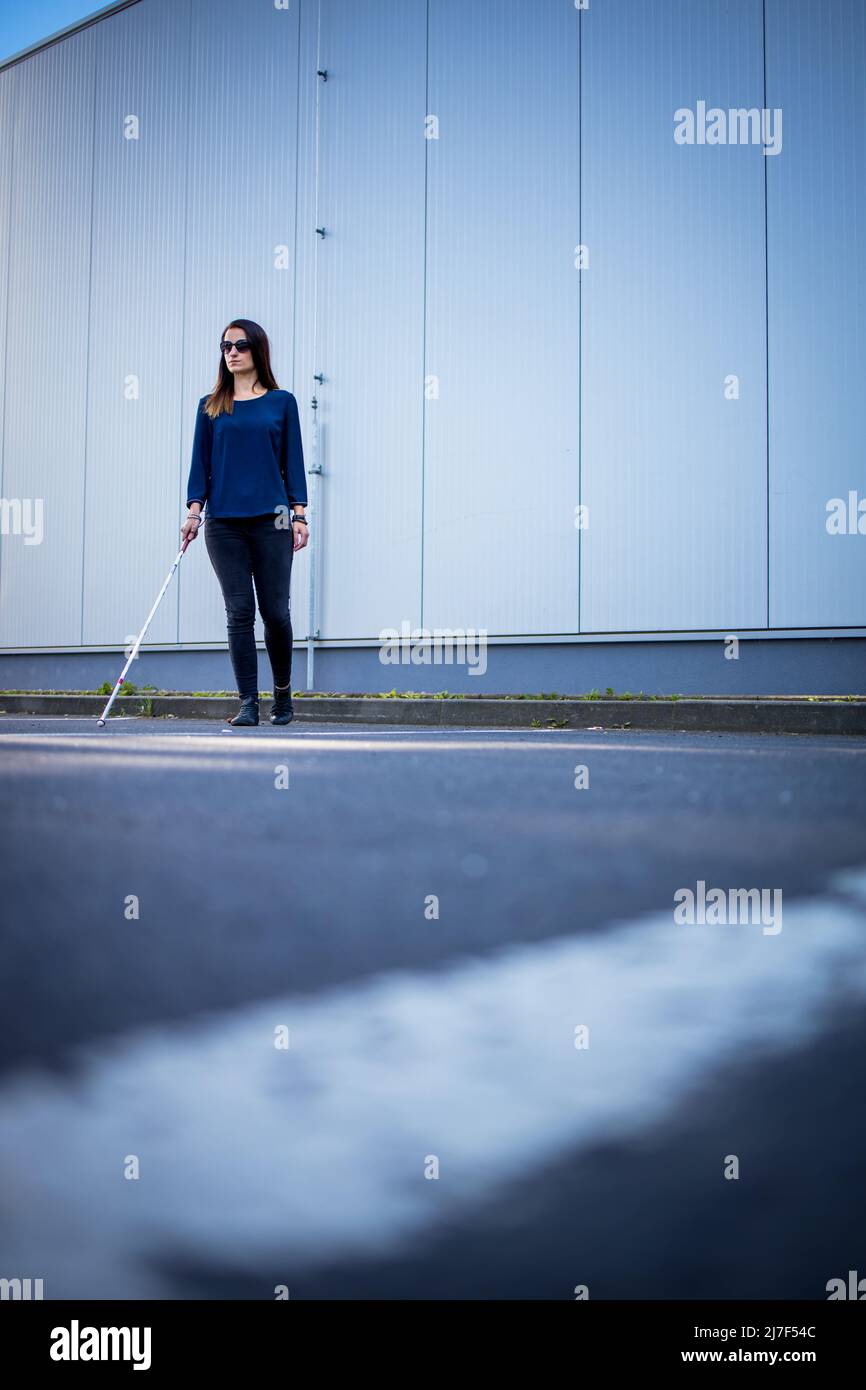 Young woman with impaired vision walking on city streets, using her ...